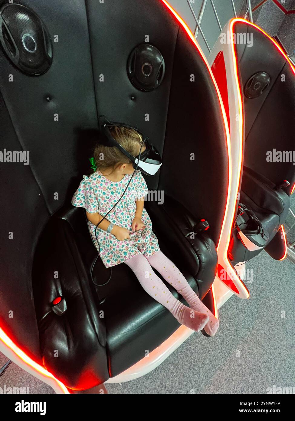 A little girl immersed in a virtual reality experience while seated in ...