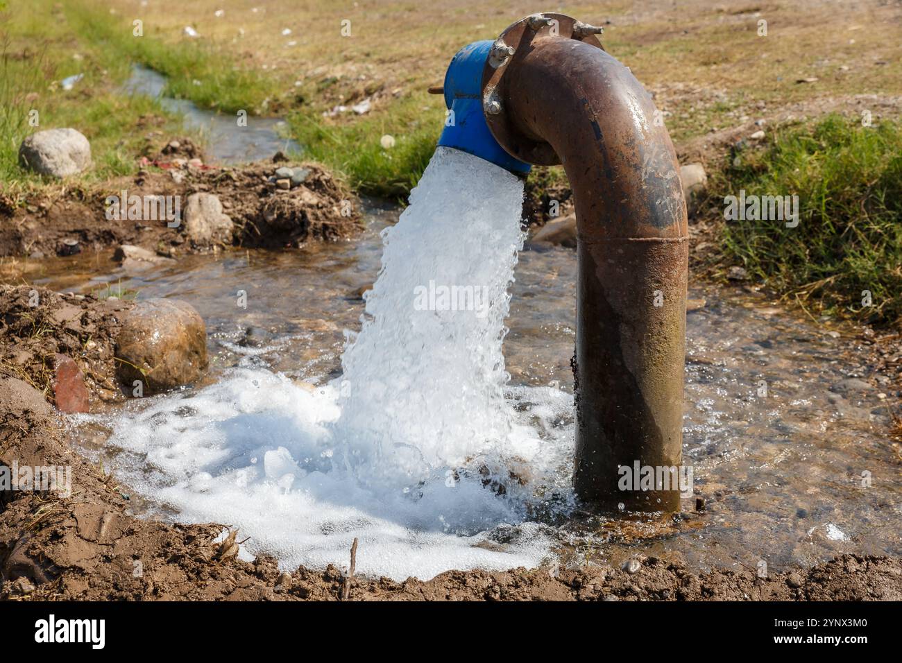 A metal pipe releases fresh water into a stream, creating bubbles and ...
