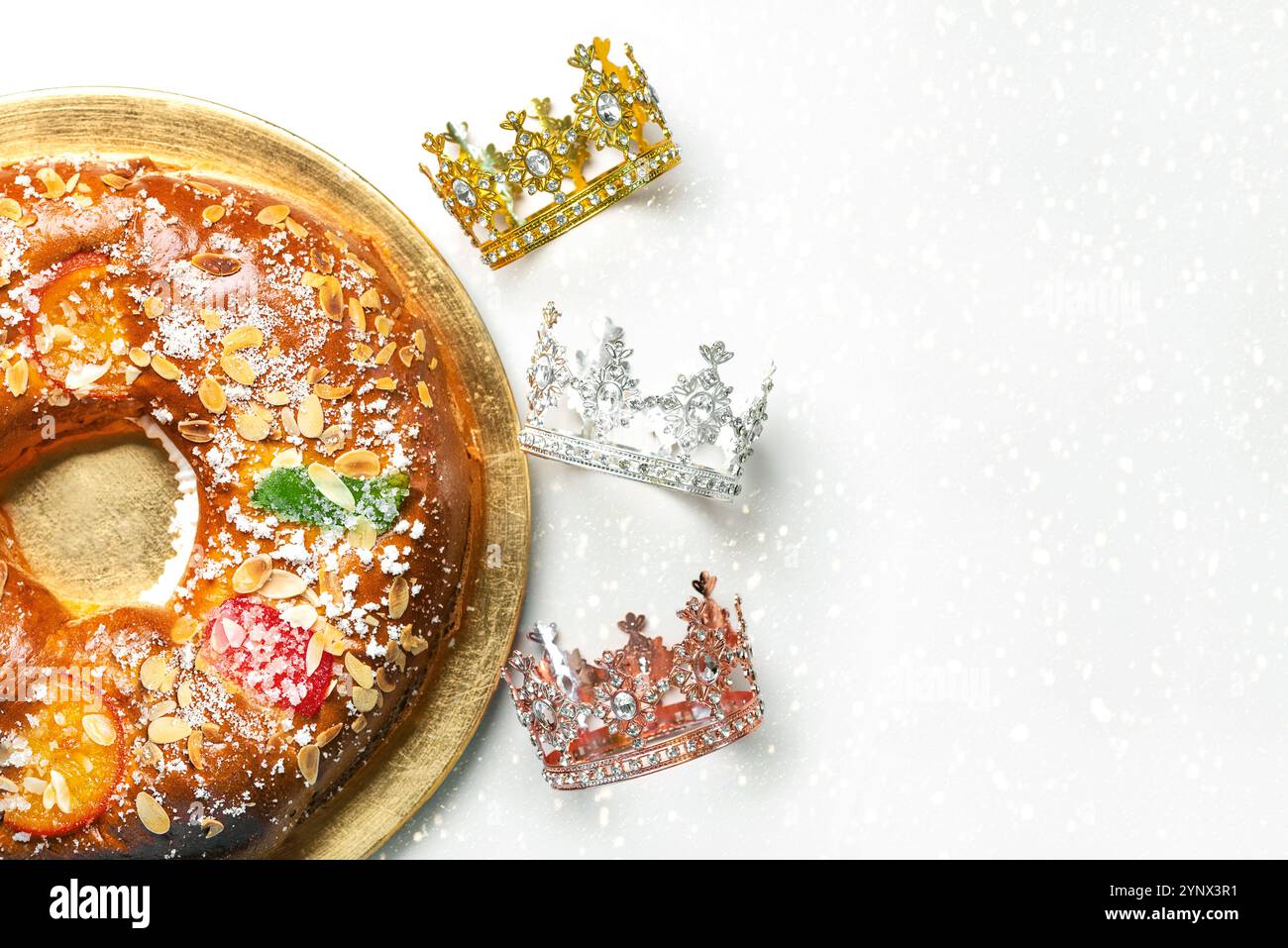 Top view of Roscon de reyes on a golden plate with crowns of the wise ...