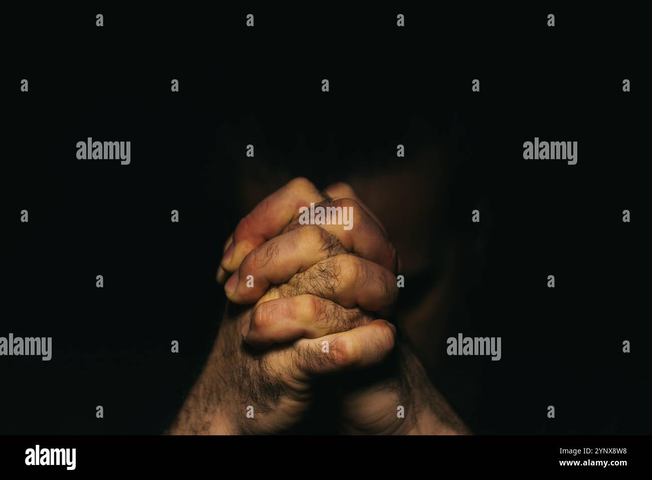 Close up of male hands desperately clasped together in a gesture of ...