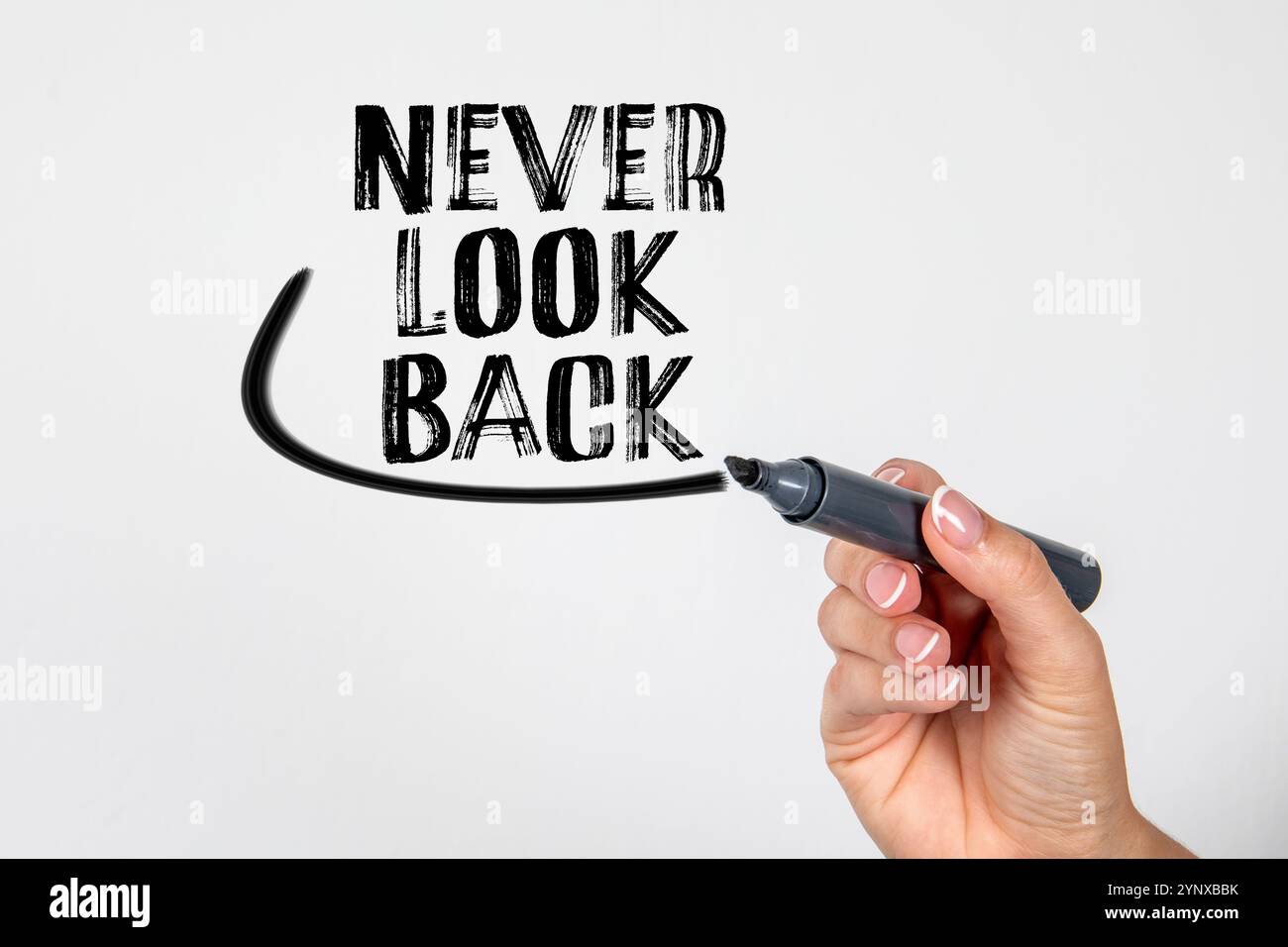 Never look back. Hand holding black marker and writing on white ...