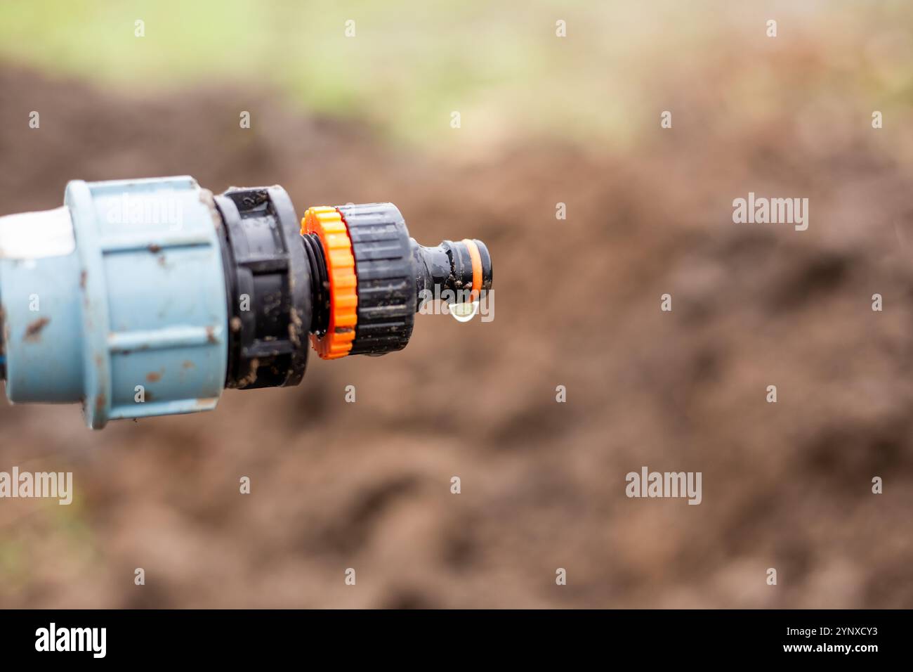 A drop of water hangs on a pipe on a quick-release nozzle for watering ...