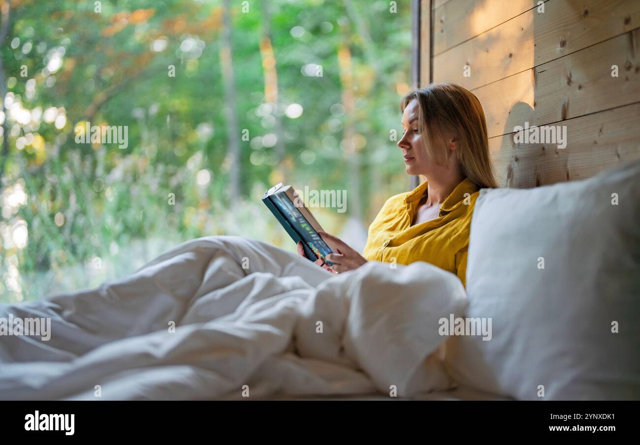 Woman reads a book while relaxing in a cabin in the forest Stock Photo ...