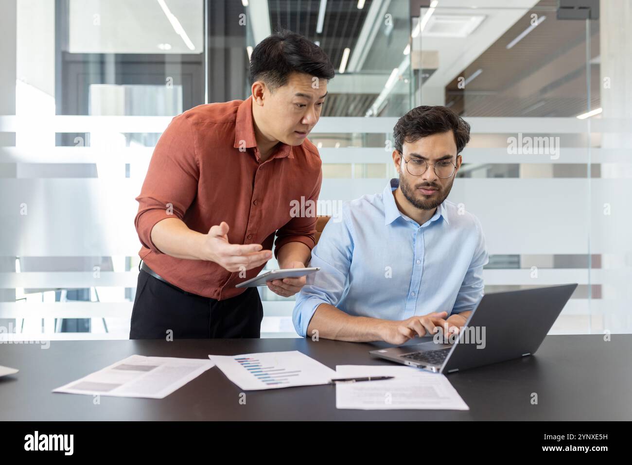 Colleagues collaborating on business project in office, using laptop ...
