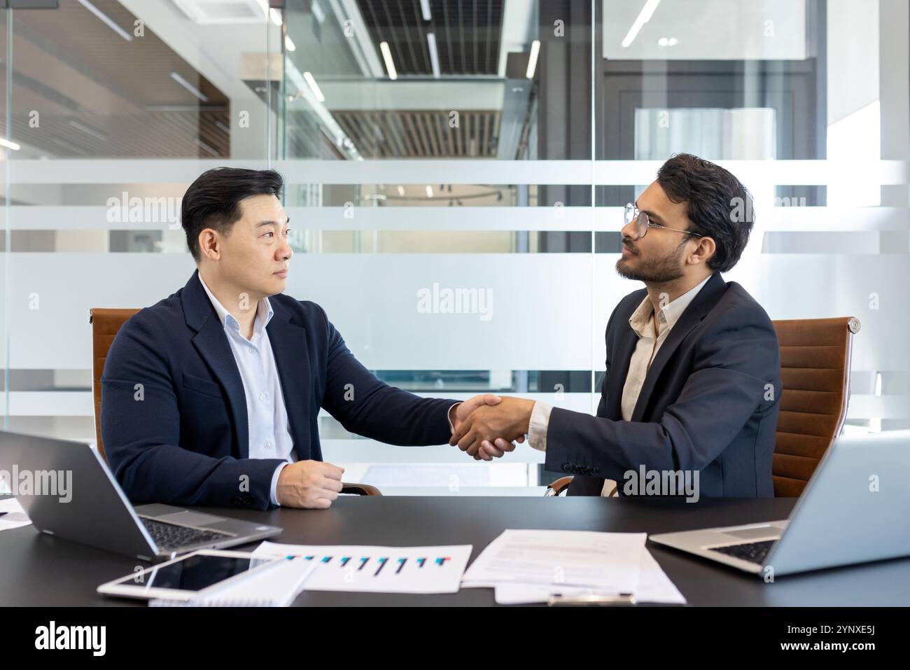Businessmen shaking hands in modern office. Image captures partnership ...
