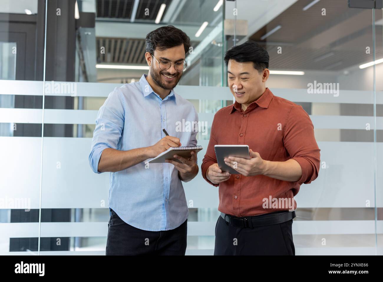 Two professionals collaborating in an office setting, using a tablet ...