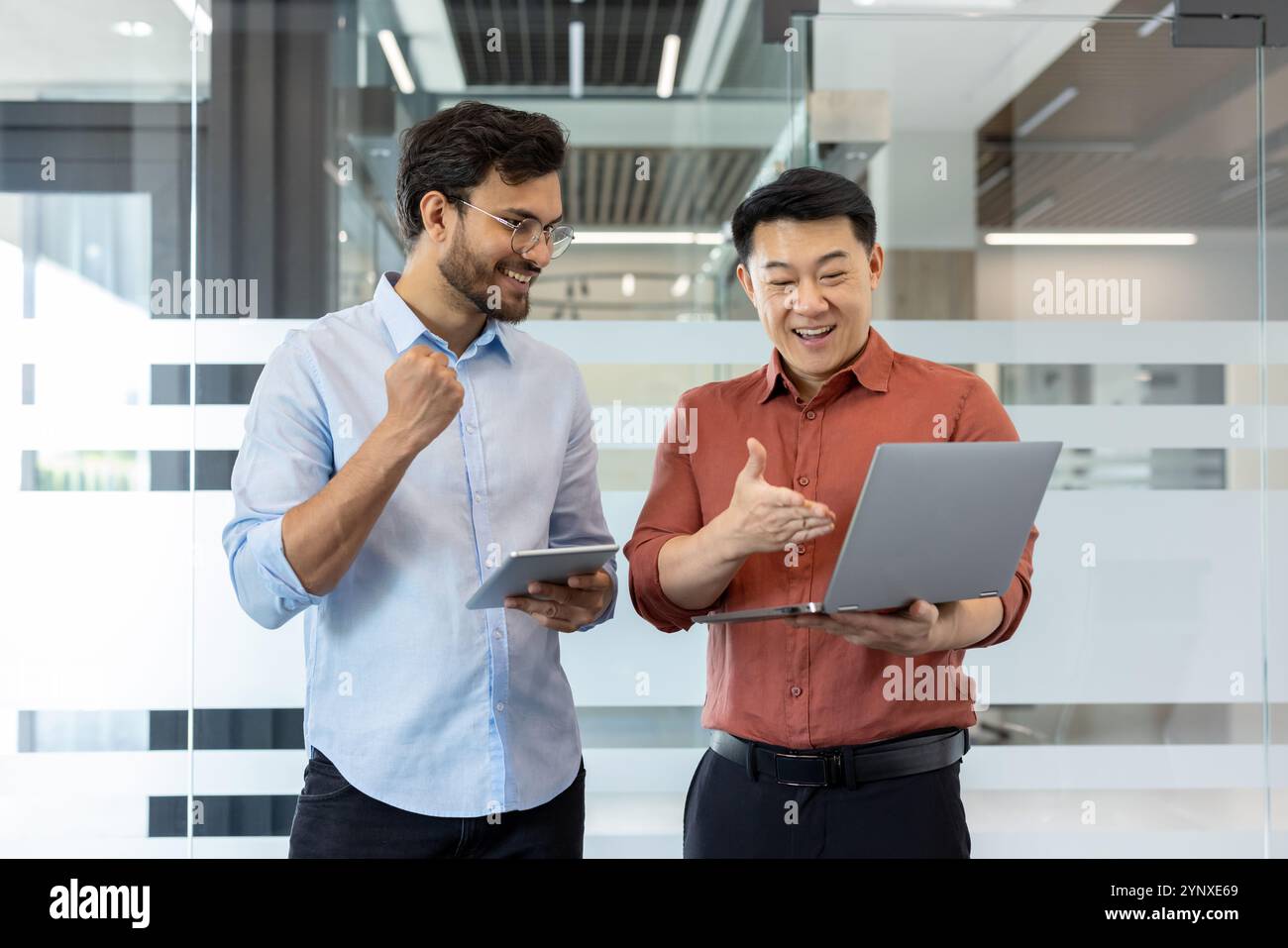 Two happy colleagues celebrate successful project in modern office. One ...