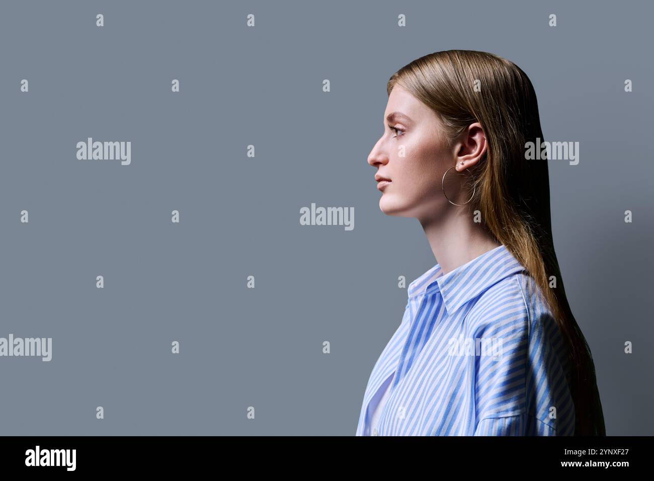Profile view, young serious female looking forward on gray studio ...
