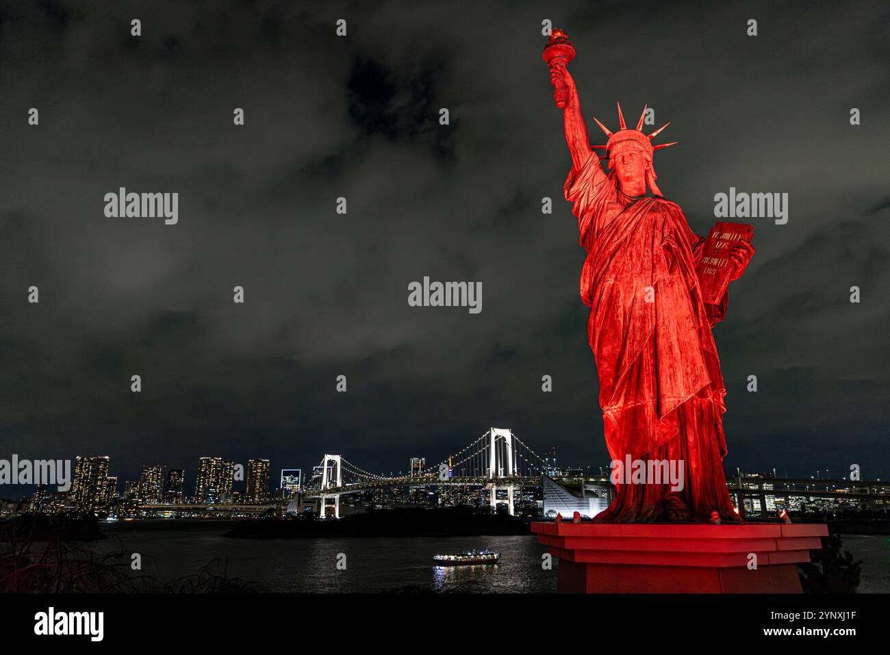 Red statue of liberty illuminating tokyo bay at night with rainbow ...