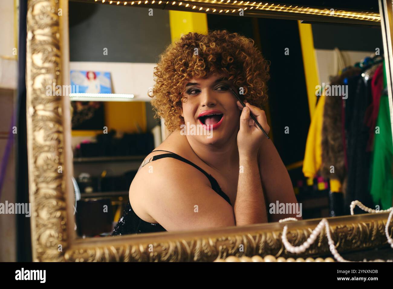 A drag queen applies makeup in a bustling backstage dressing room ...