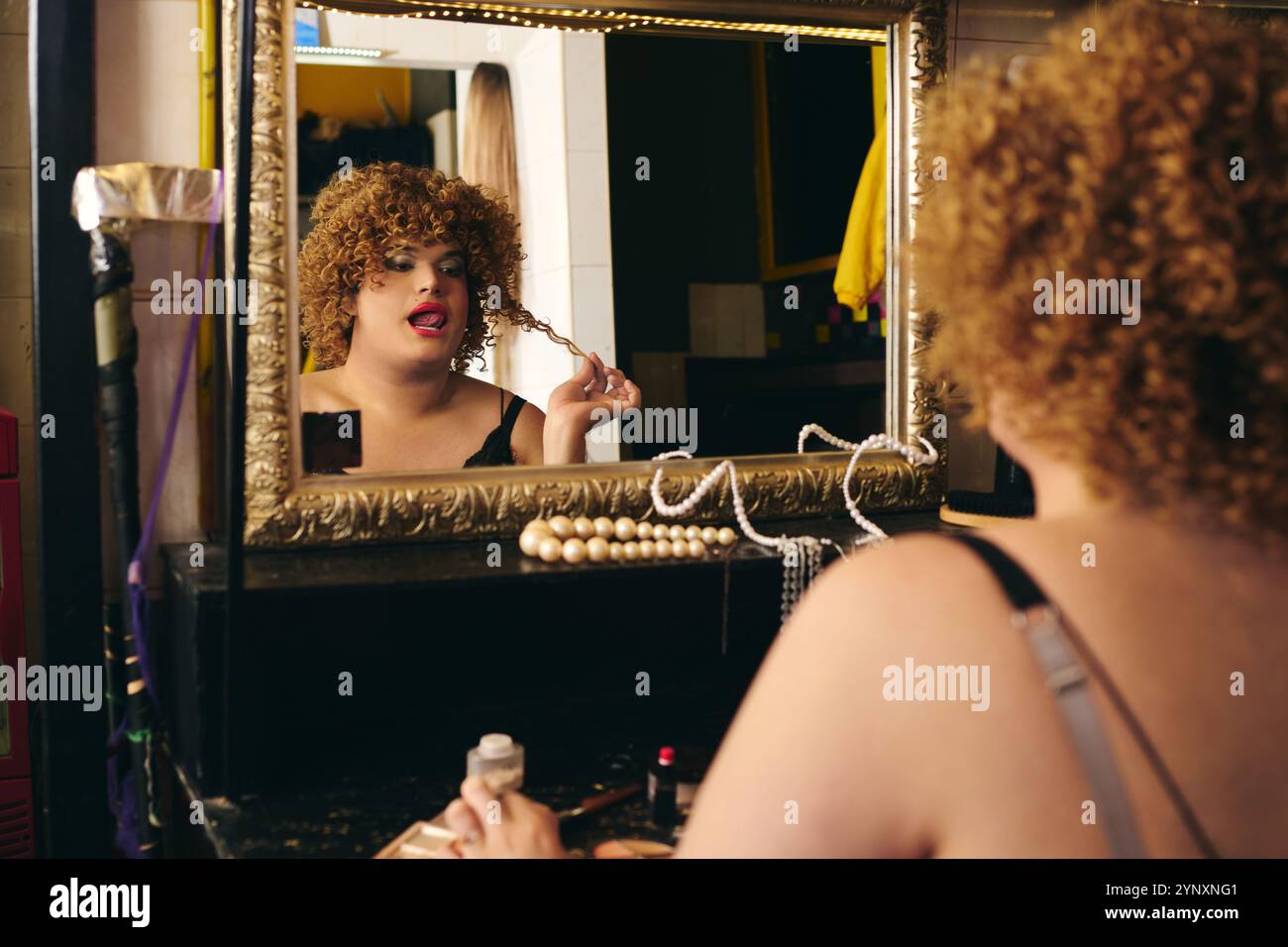 A drag queen perfects their makeup in the backstage dressing room ...