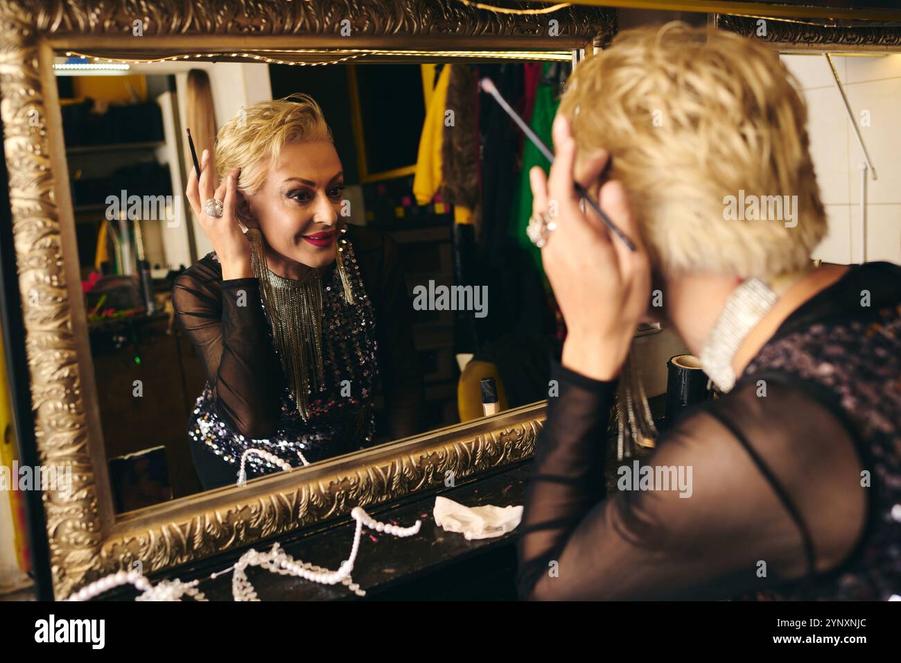 An androgynous drag performer applies makeup in a backstage dressing ...