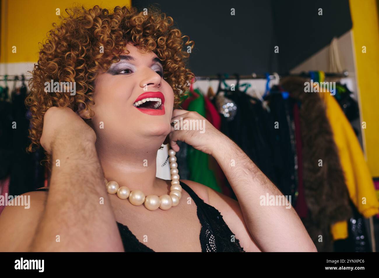 In the busy dressing room, a drag queen happily wearing accessories ...