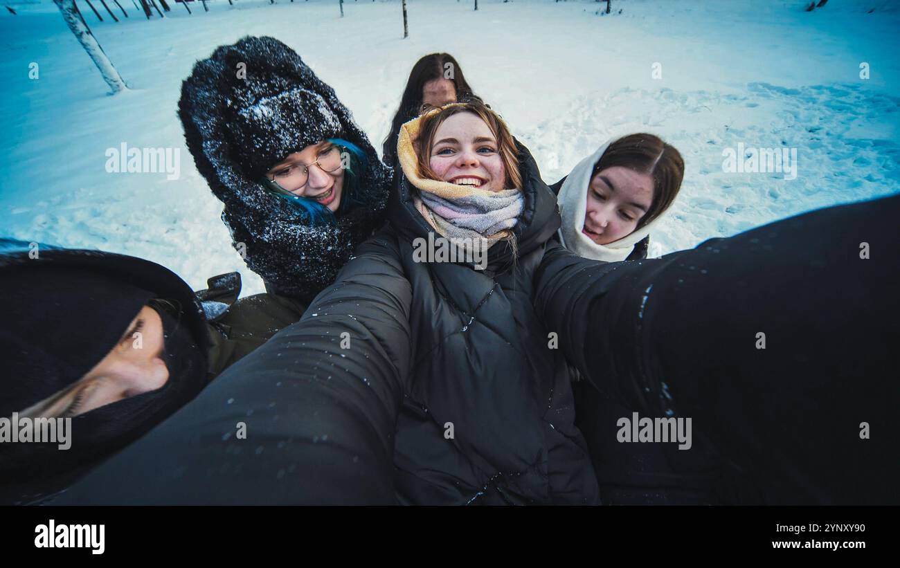 Happy students in cozy winter attire capturing a group selfie in a ...