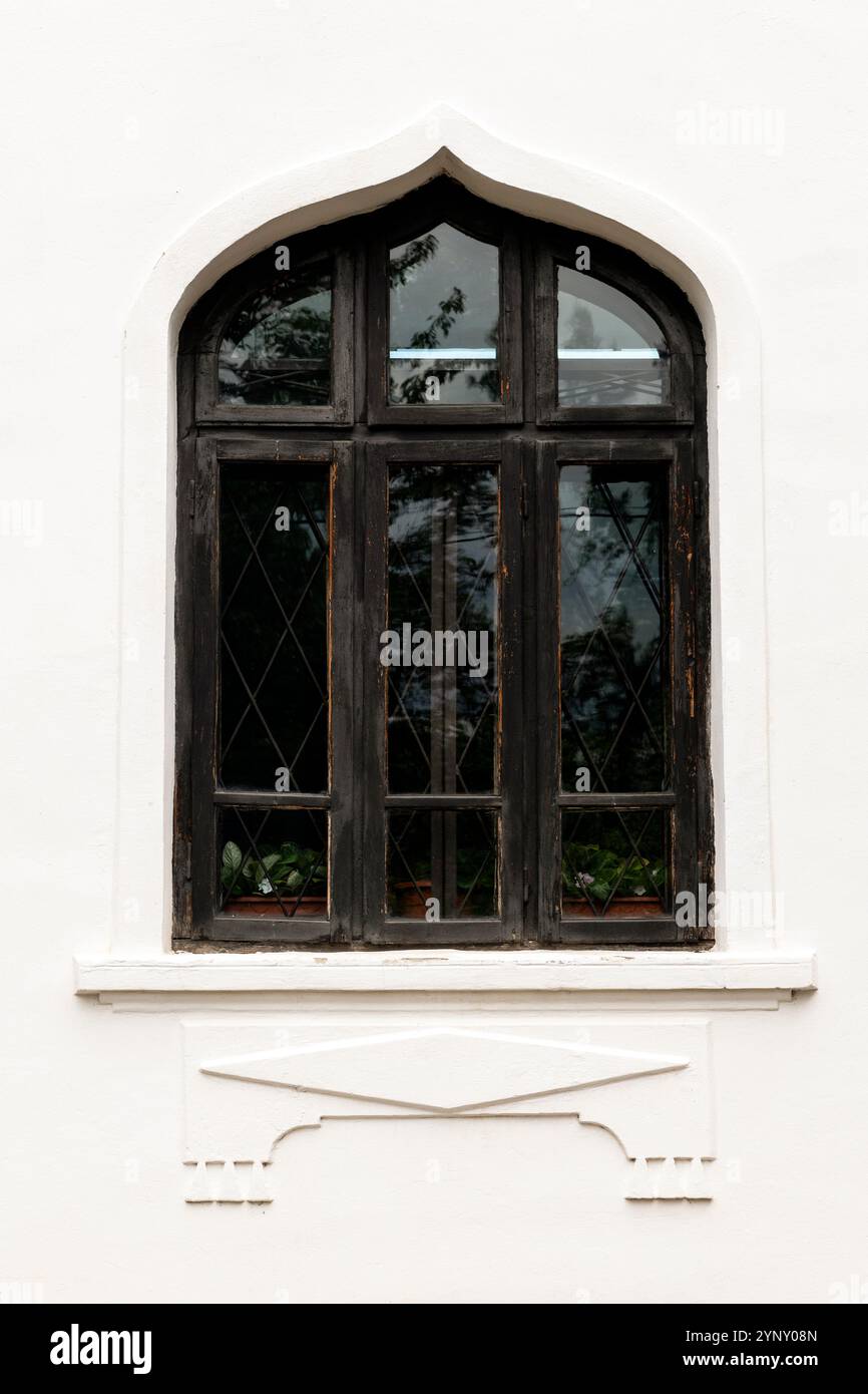 Elegant black arched window with intricate detailing on a white ...