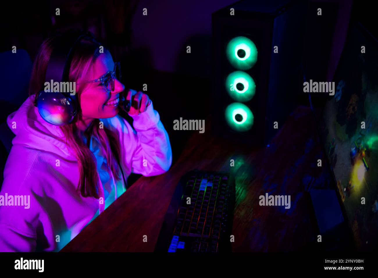Young female gamer enjoying a virtual adventure at home in neon light ...