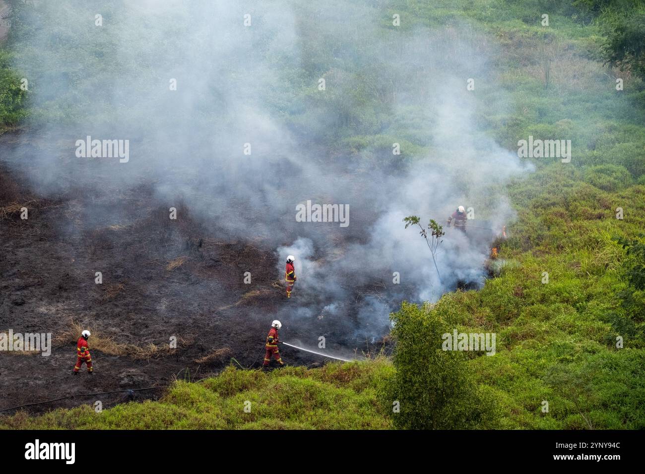 Aerial view of four Firefighters putting out a fire in a rural ...