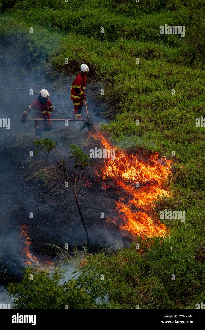 Two Firefighters putting out a fire in a rural landscape, Malaysia ...