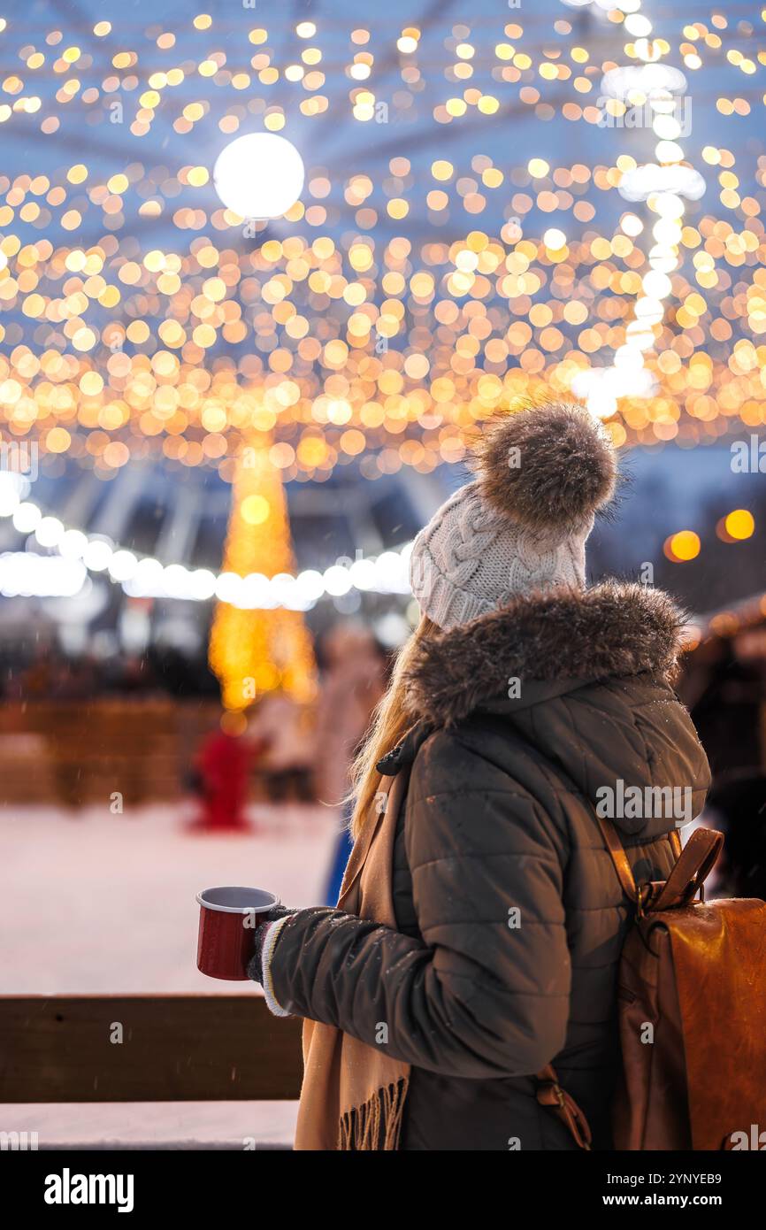 Woman is looking to people ice skating on rink. Christmas market and ...