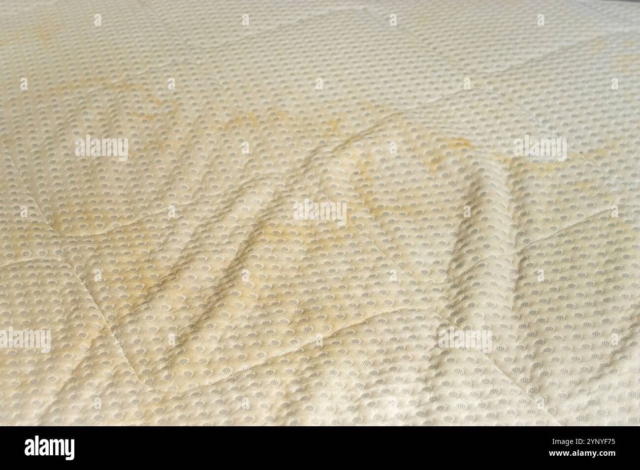 A dirty mattress with yellow stains. Cleaning textile at home concept ...