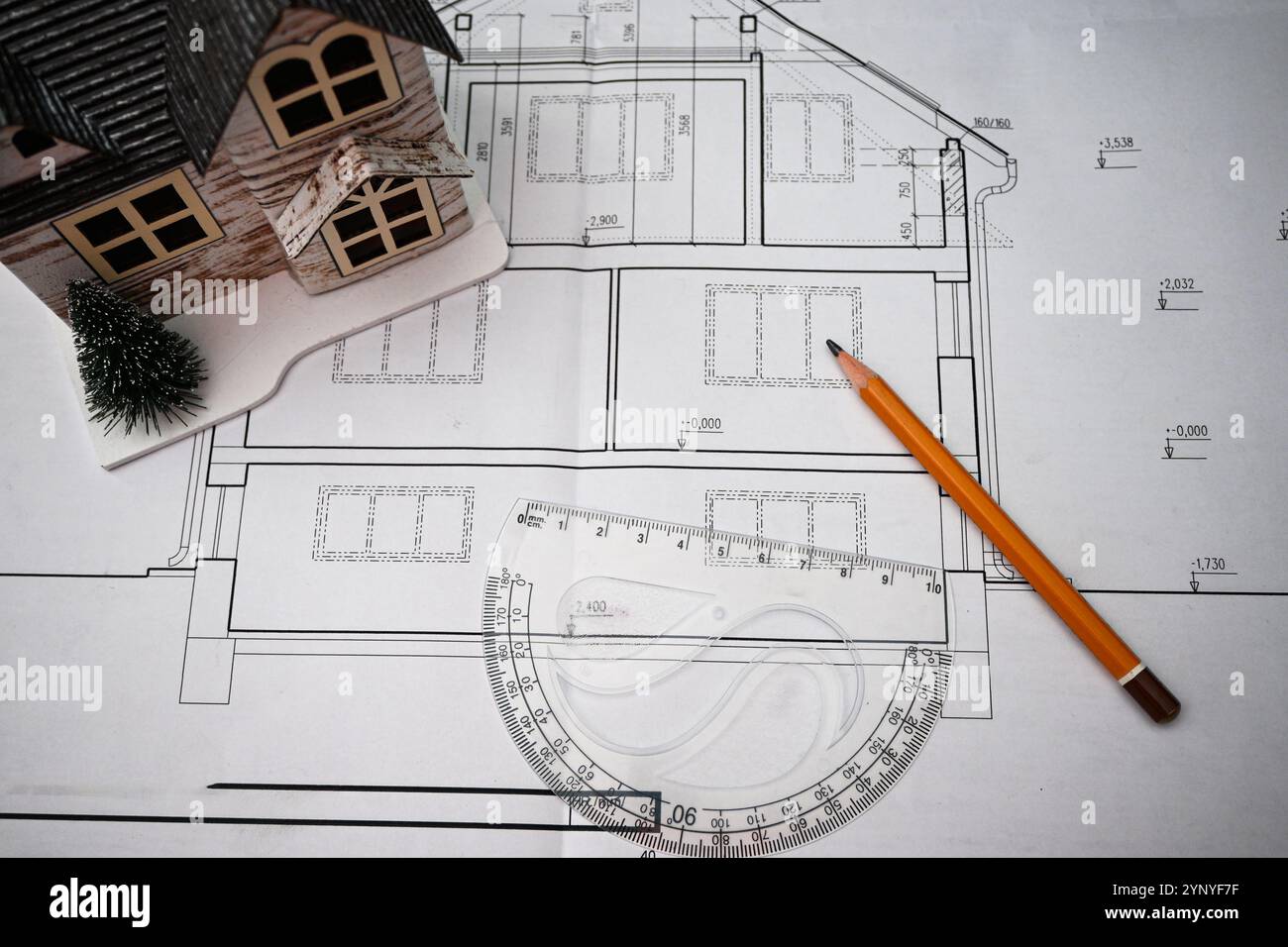 Model house standing on architectural blueprint with pencil and ...