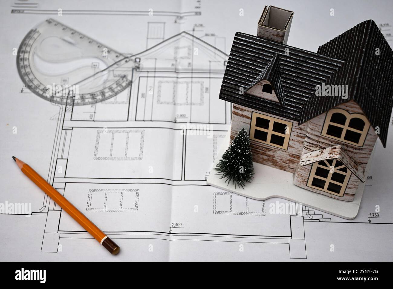 Model house standing on architectural blueprint with pencil and ...