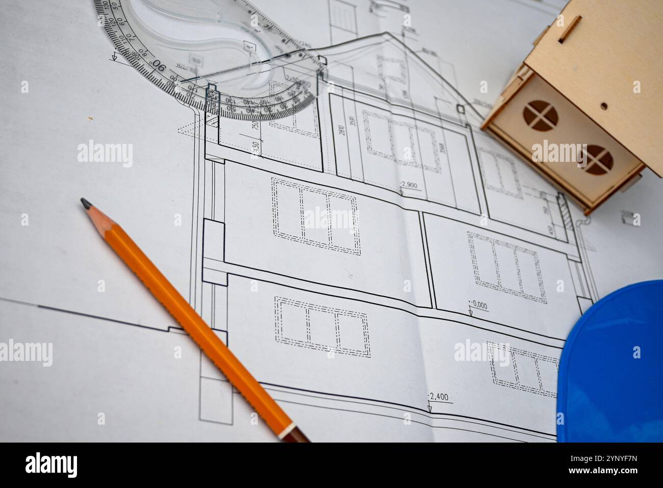 Model house standing on architectural blueprint with pencil and ...