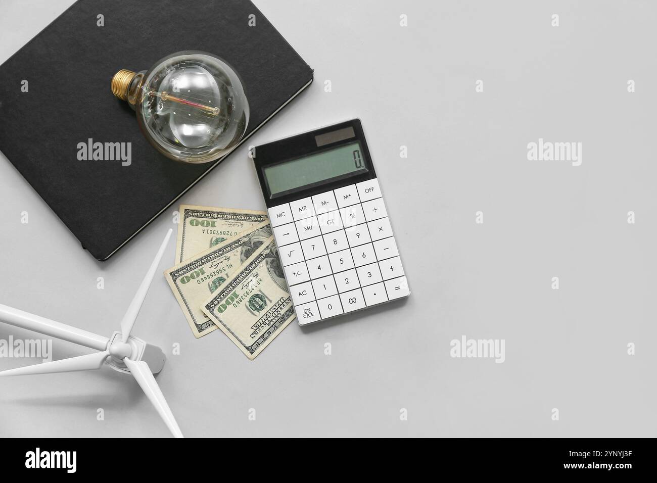Wind turbine with calculator, money, light bulb and notebook on grey ...