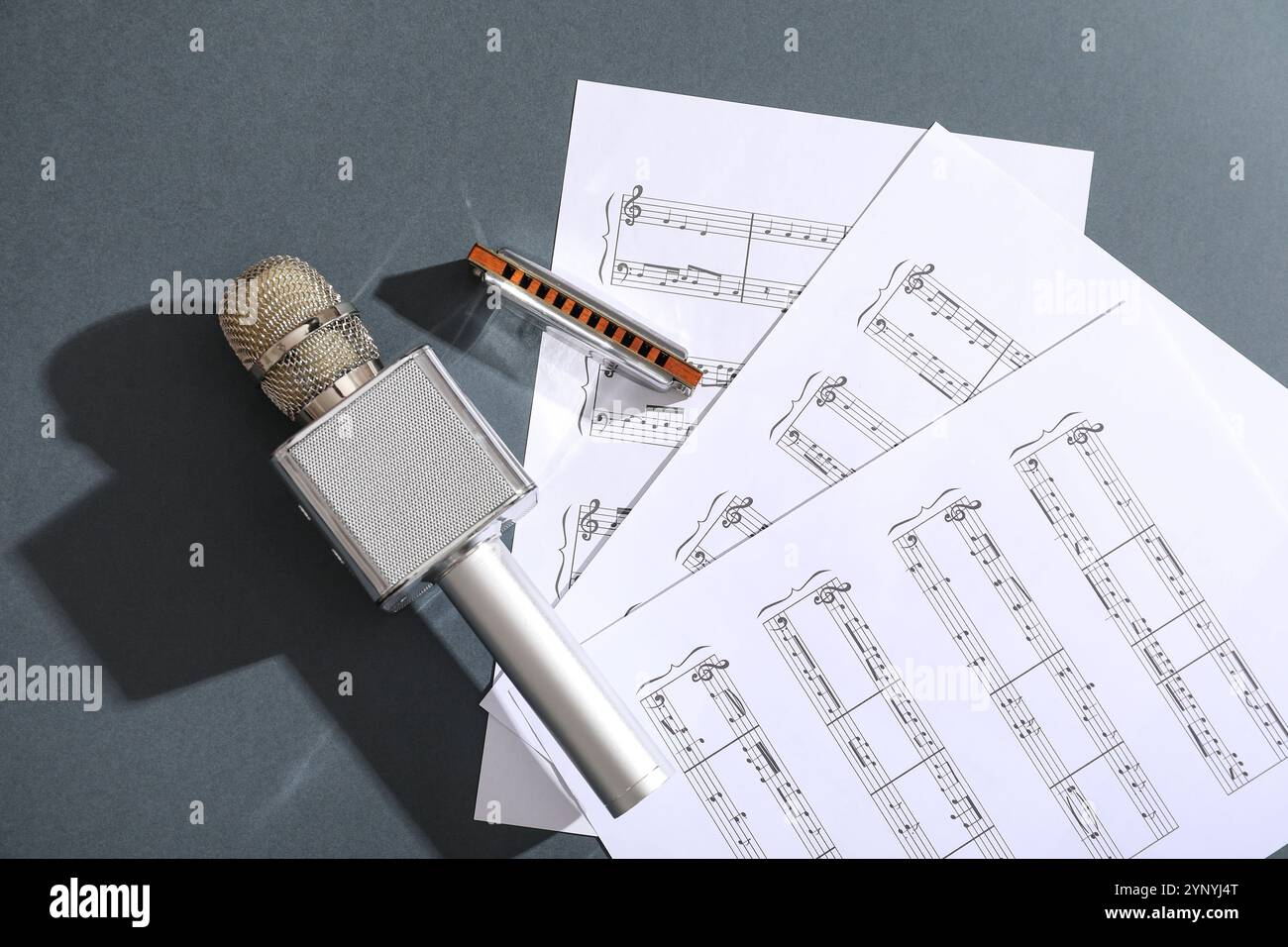 Harmonica, microphone and music sheets on dark background Stock Photo ...