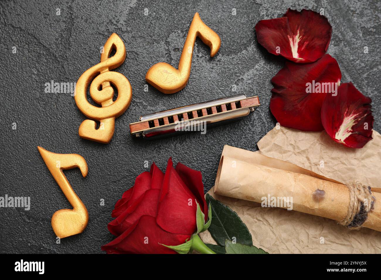 Composition with harmonica, music notes, scroll and rose flower on dark ...