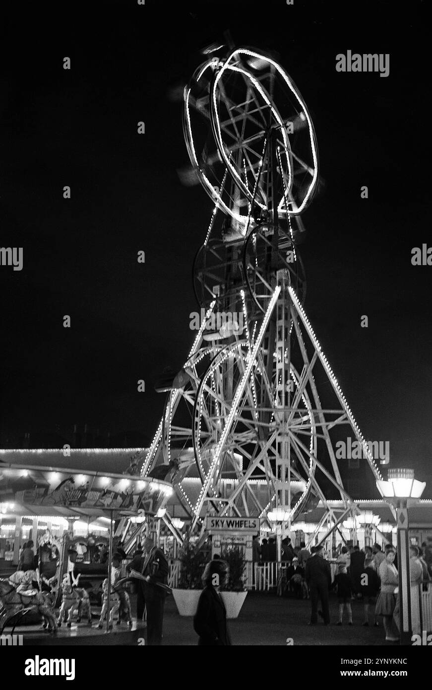 Fairground at night with sky wheels and roundabout illuminated, and ...