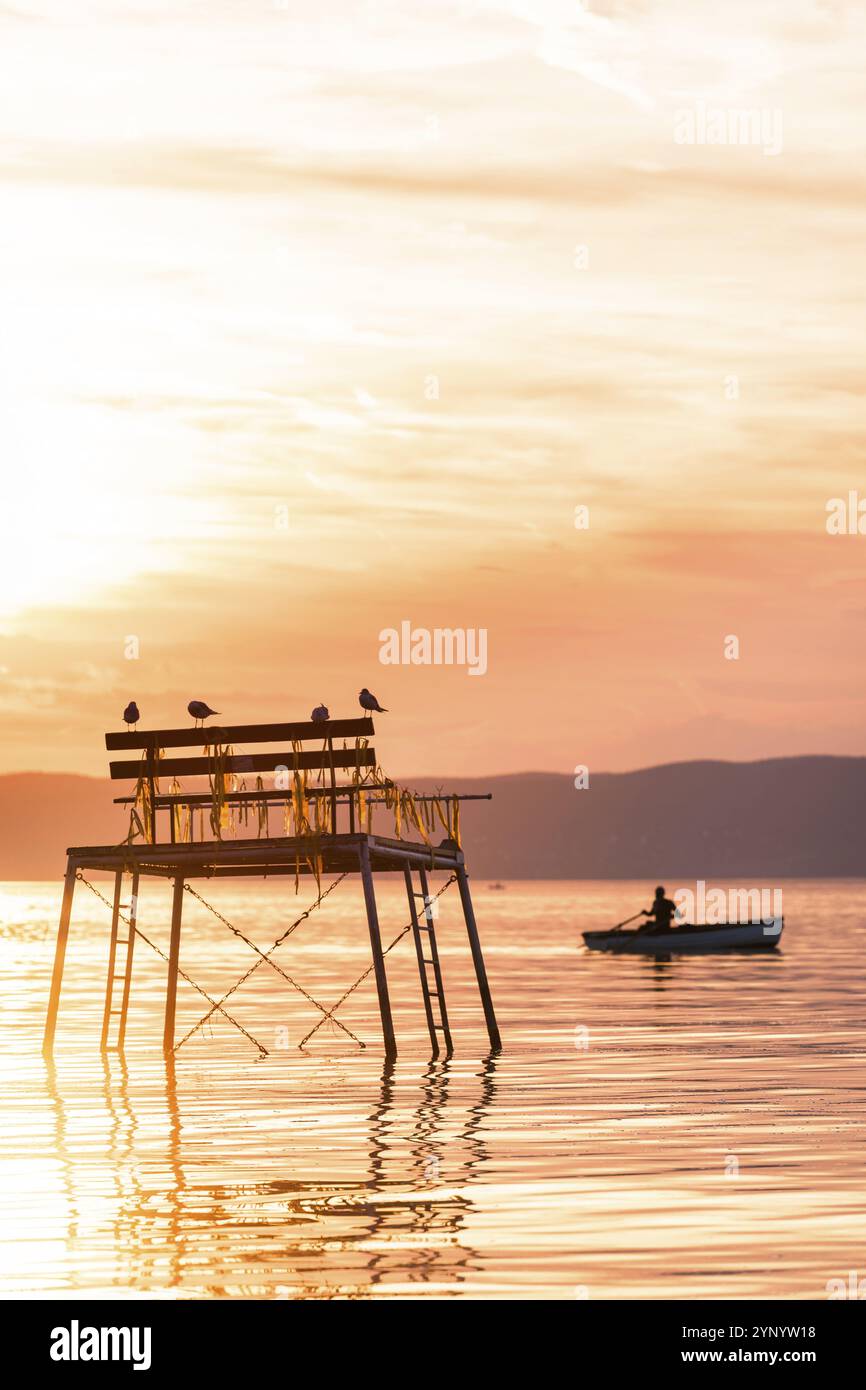 Fisher stand and fisher in rowing boad at sunset at lake Balaton Stock ...