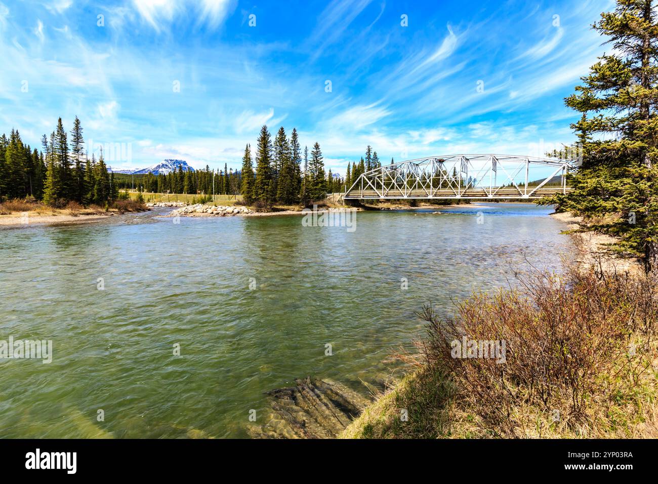A bridge spans a river with a green waterway. The bridge is white and ...