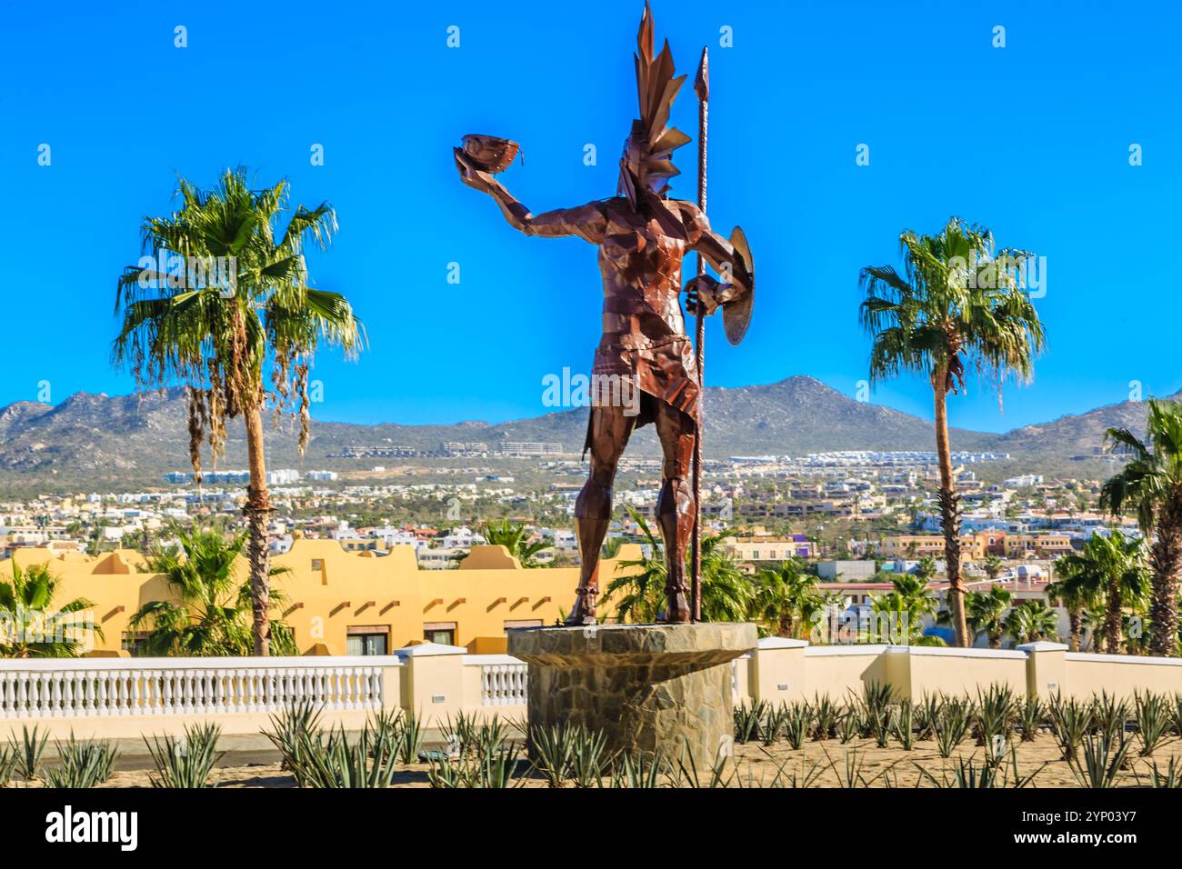 A statue of a warrior stands in front of a palm tree. The statue is ...
