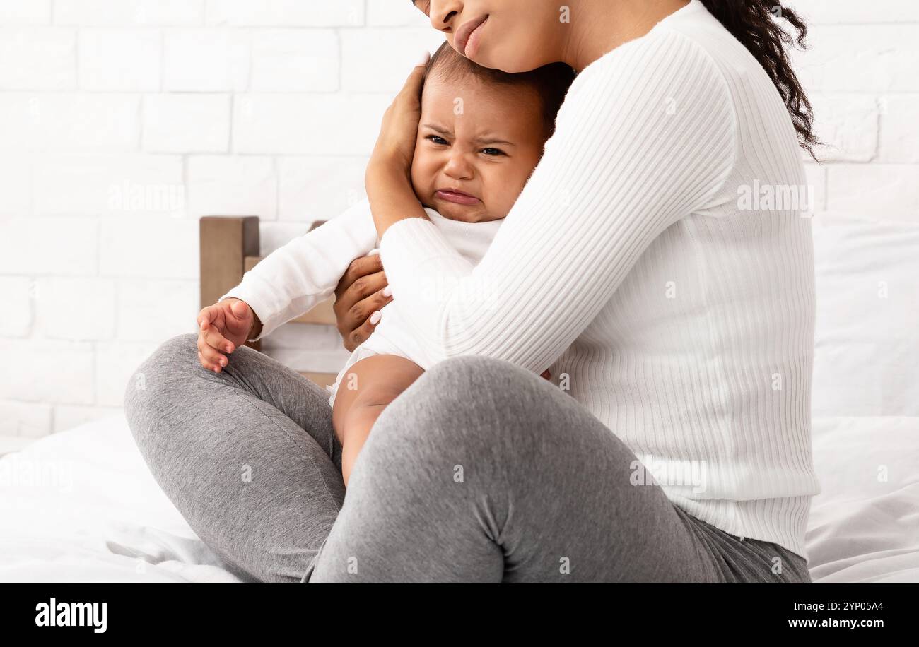 African Mother Hushing Crying Newborn Baby To Sleep In Bedroom Stock ...