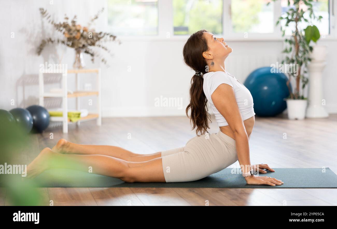 Girl practicing yoga with in studio, performing wind release pose Ardha ...
