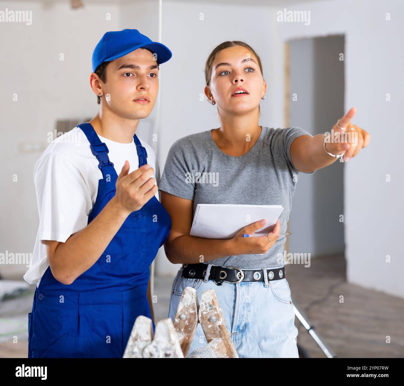 Female designer with papers talking to contractor in building during ...