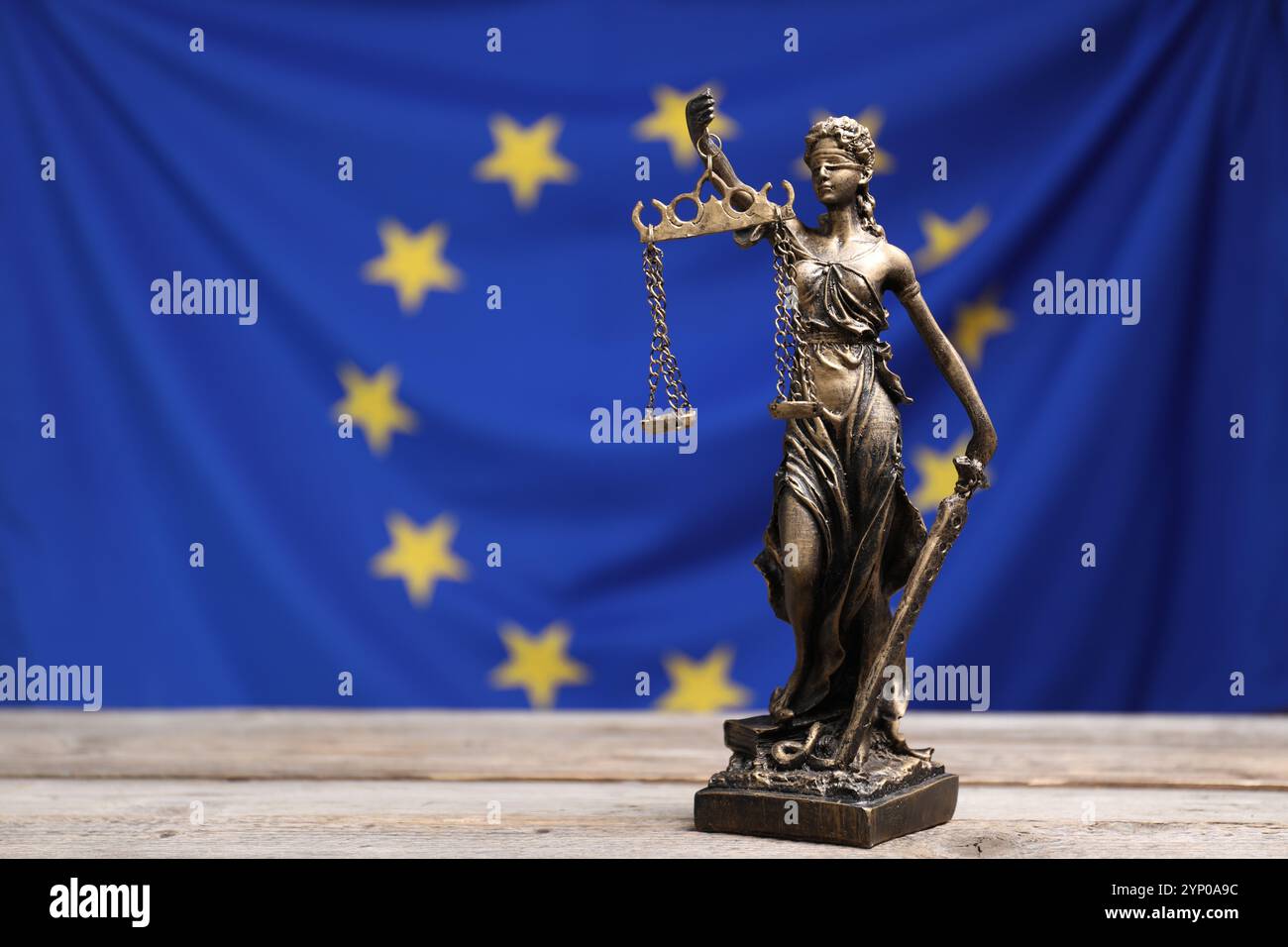 Figure of Lady Justice on wooden table against European Union flag ...