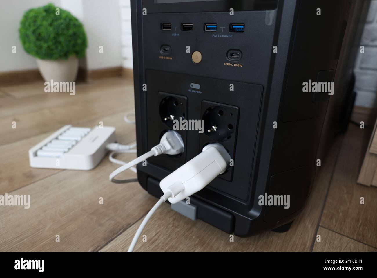 Modern portable power station with attached device indoors, closeup ...