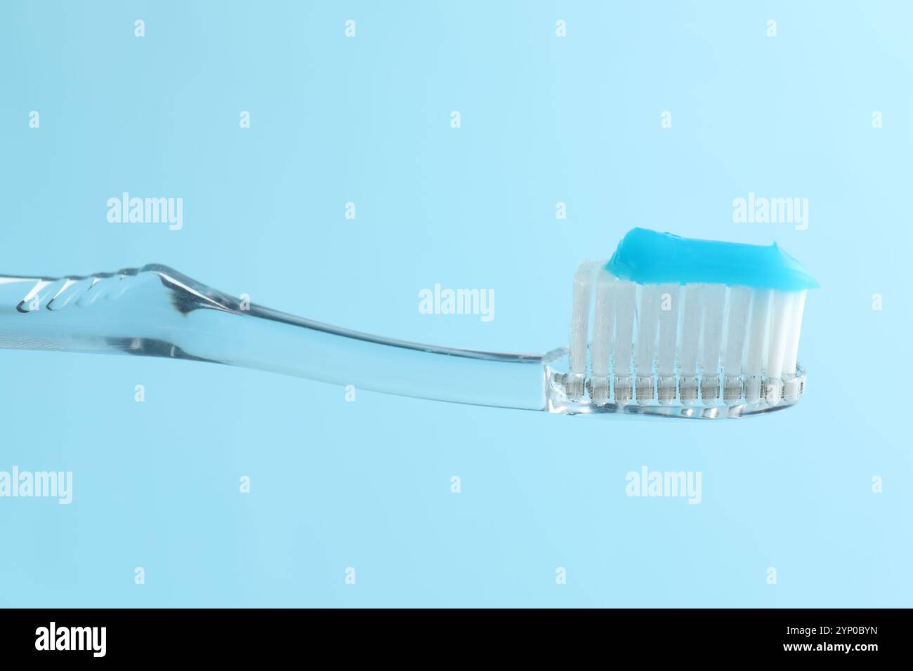 Toothbrush with toothpaste in air on light blue background, closeup ...
