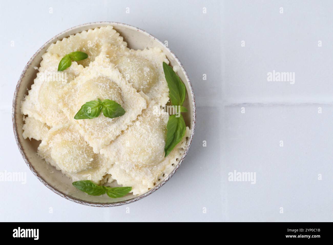 Delicious ravioli with cheese and basil on white tiled table, top view ...