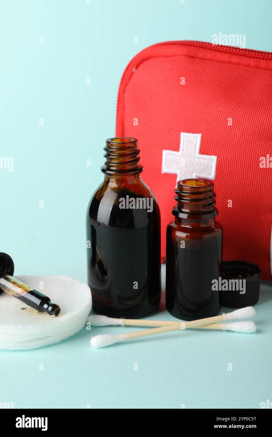 Topical iodine and other first aid kit components on light blue ...
