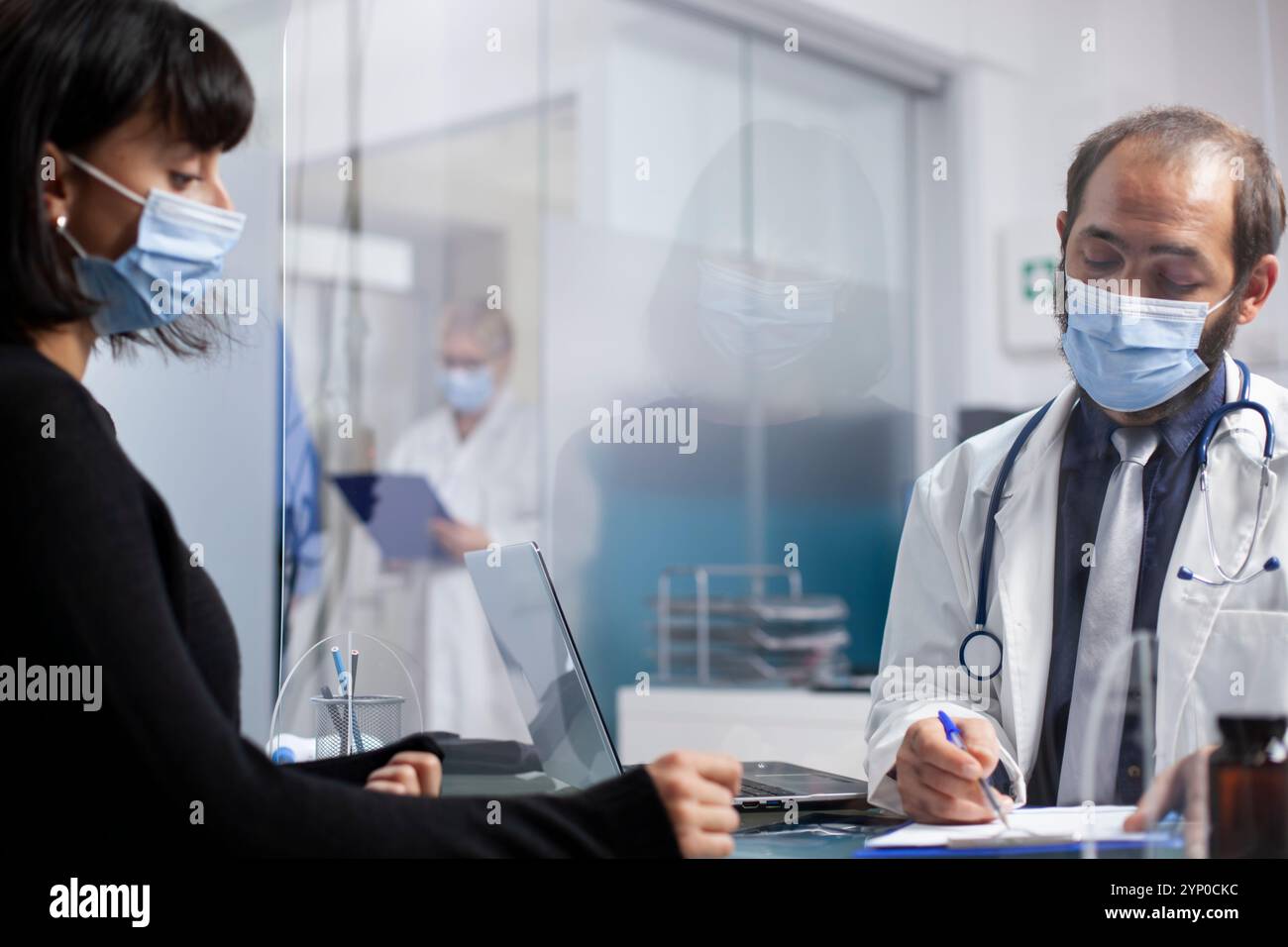 Bearded doctor writing notes for female patient during medical checkup ...