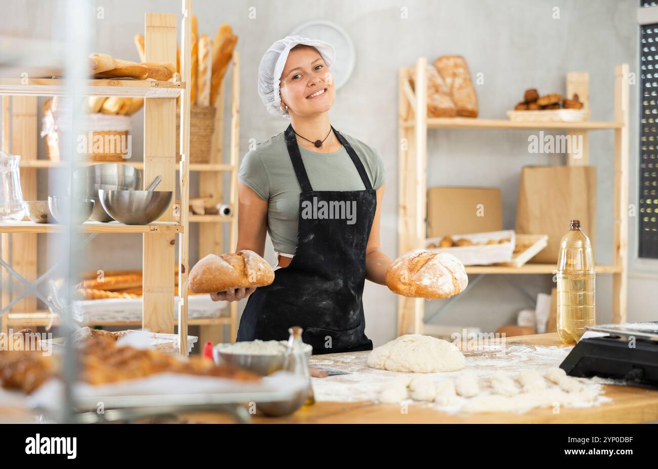 Bakery woman employee holds ready made bread of bread Stock Photo - Alamy
