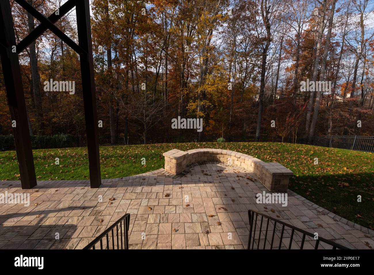 A picturesque autumn backyard with a curved stone patio and steps ...