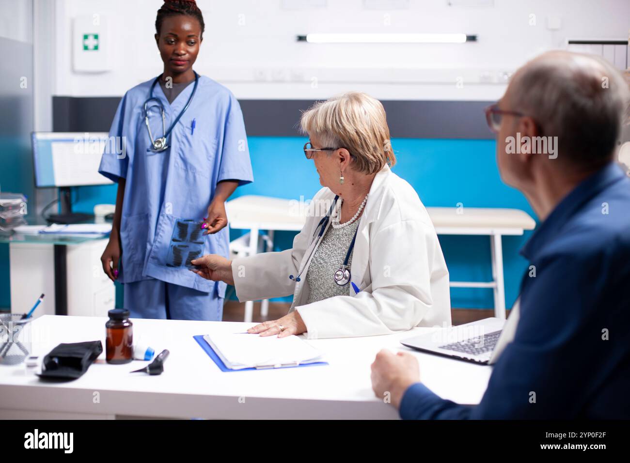 Black healthcare worker gives radiograph to older doctor as male ...