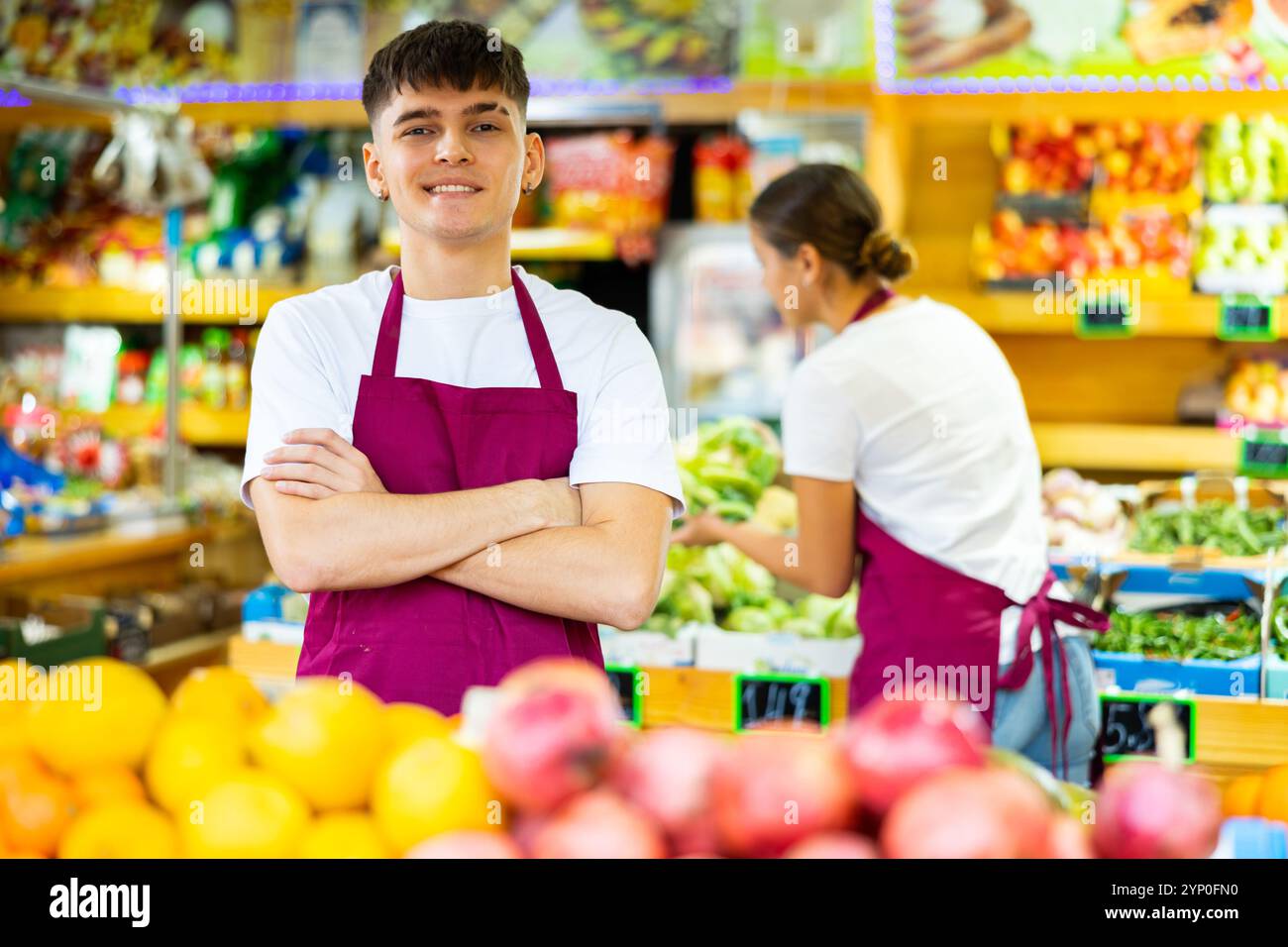 Portrait of positive young salesman in the vegetable section of grocery ...
