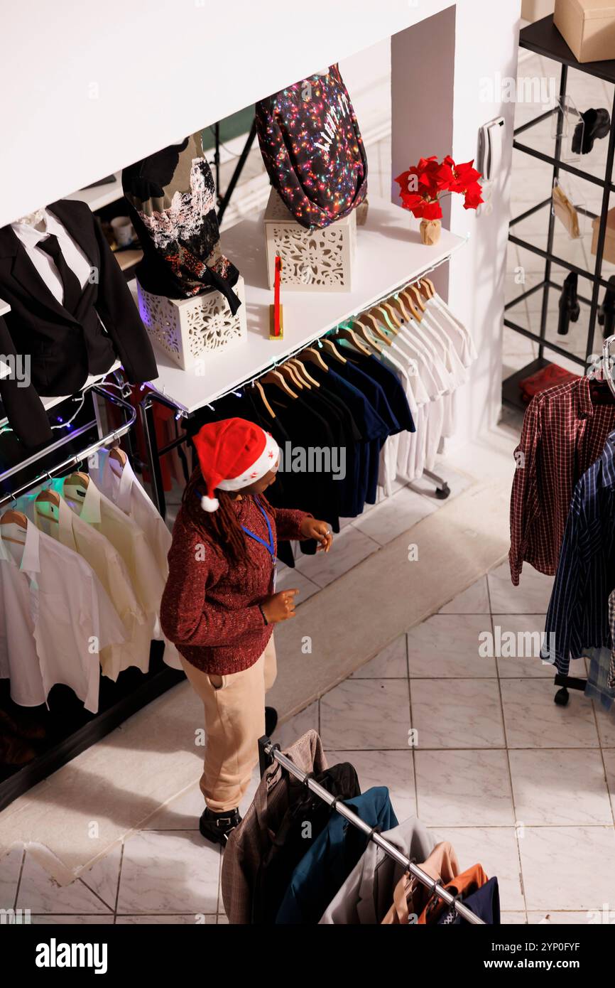 Retail worker arranging clothes on racks in clothing store, helping ...