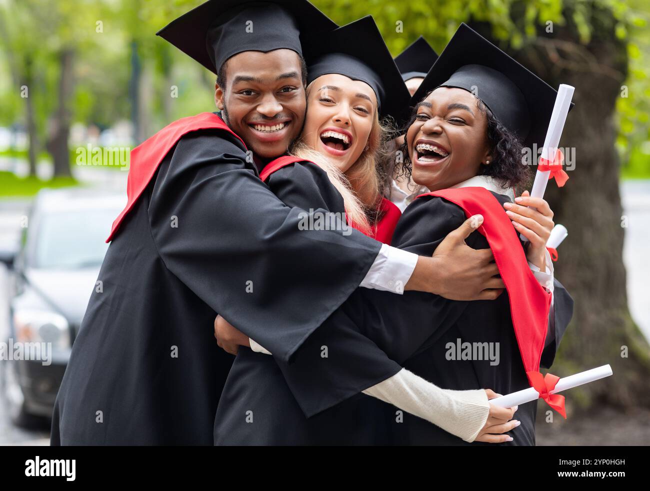 Black guy and two young ladies in graduation costumes Stock Photo - Alamy