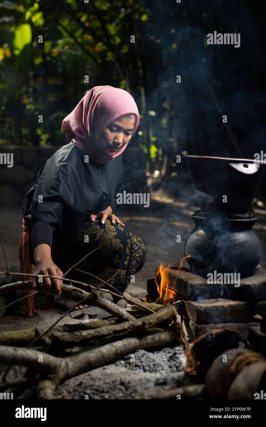 A woman steaming rice using a traditional cooking method, Lombok, West ...